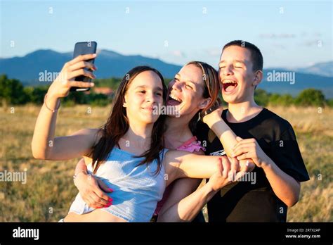 A Happy Aunt Takes A Selfie With Her Nephews On A Hill In Nature During