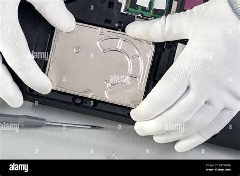 Technician Hands Removing An Old Mechanical Hard Disk From A Laptop