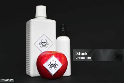 인간에게 위험한 농산물의 농약 잔류물의 개념 검은 배경에 독 기호 스티커가 있는 빨간 사과와 흰색 병을 보여주는 살충제에 대한