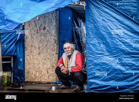 An Elderly Man Is Seen Sitting In Front Of The Tent He Had Set Up