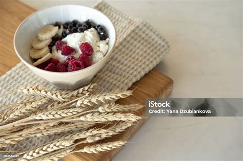베리와 코티지 치즈의 맛있는 건강한 아침 식사 코티지 치즈와 열매가 있는 흰색 접시가 하얀 탁자 위에 나무 판위에 서 있고 그