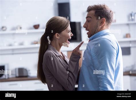 Side View Of Angry Woman Pointing With Finger And Screaming At Husband