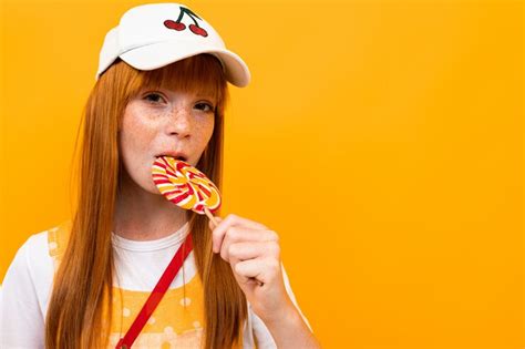 Premium Photo Stylish Red Haired Girl Sucks A Lollipop Over Background