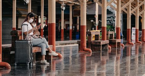 기차역에서 아시아 관광 십대 소녀가 온라인 지도 소셜 미디어 체크인 또는 티켓 예약을 위해 스마트폰을 사용합니다 현대 여행 앱 기술 고독한 여행자 여름 휴가 철도