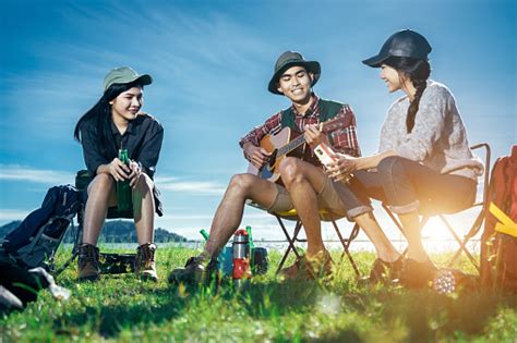 아시아 친구 들의 자에 앉아 노래 그룹 기타 연주 하 고 몇 가지 맥주와 함께 텐트 밖에 서 물 마시는 동안 그들은 주말 휴가