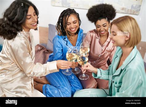 Positive And Multiethnic Girlfriends In Colorful Pajama Toasting With