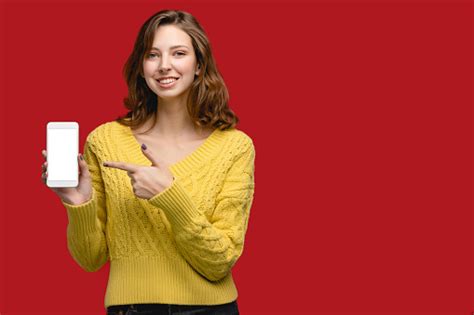 스튜디오에서 빨간색 배경에 스마트 폰을 가진 젊은 여성 그녀는 노란색 스웨터를 입고 설계를 위한 공간을 복사합니다 감정이 있는 개념 14에 대한 스톡 사진 및 기타 이미지