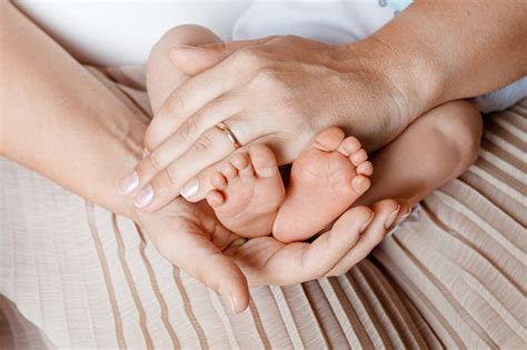 어머니의 손에 아기 발 여성 모양의 손 클로즈업에 작은 신생아 아기의 발 엄마와 그녀의 아이 행복한 가족 개념입니다 출산의