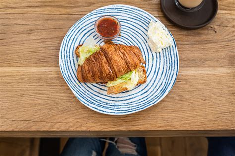 접시에 구운 치즈와 샐러드 카페 또는 커피 숍의 나무 테이블과 크루아상 맛있는 샌드위치 아침 또는 점심 식사 개념에 대한 스톡