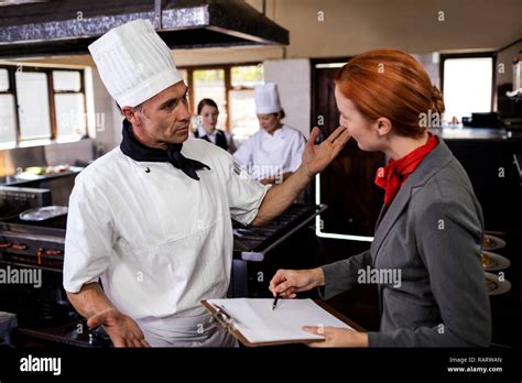 Female Manager And Male Chef Interacting With Each Other In Kitchen