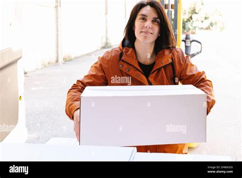 Content Female Forwarder Worker Looking At Camera While Loading Heavy White Box Into Truck