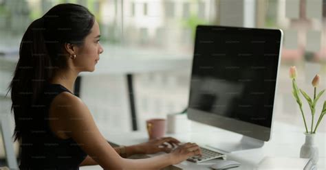 용품과 꽃 꽃병이 있는 작업대에서 컴퓨터로 일하는 여성 회사원의 측면 모습 사진 Unsplash의 랩톱 이미지