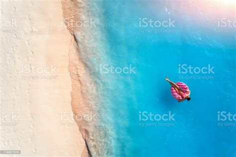 여름의 석양에 파도와 맑은 푸른 바다에서 도넛 수영 반지와 수영 하는 젊은 여자의 공중 보기 소녀 푸른 물 모래 해변과 열 대 공중 풍경입니다 평면도 여행 사람들에 대한