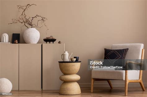 회색 안락의자 짙은 베개 베이지색 찬장 나무 커피 테이블 가지가 있는 꽃병 둥근 베개 개인 액세서리가 있는 거실 인테리어의 아늑한 구성 가정 장식 템플렛 0명에 대한 스톡