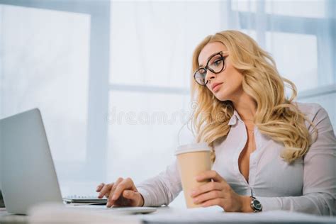 Beautiful Businesswoman Working At Laptop In Office And Holding Coffee