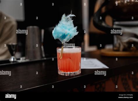 Colorful Cocktail With Cotton Candy Garnish On Bar Counter At Evening