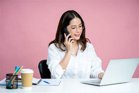 Asian Woman Wearing Glasses And A White Shirt Sits At A White Desk She