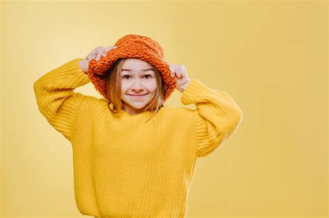 귀여운 십대 소녀 입고 오렌지 푹신한 모자와 노란색 스웨터 노란색 배경에 포즈 Z세대에 대한 스톡 사진 및 기타 이미지 Z