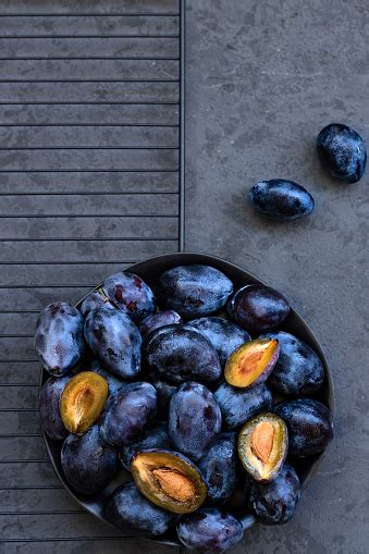신선한 익은 파란색 전체와 어두운 회색 배경에 검은 접시에 자두를 자른 상위 뷰 낮은 키 사진 클로즈업 플랫 레이 구성 공간을 복사합니다 자두에 대한 스톡 사진 및 기타