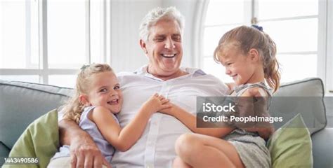 행복한 가족 은퇴 노인이 소파에서 아이들과 놀고 유대감 행복 웃음 미소 노인과 할아버지는 집에서 소파에서 좋은 시간을 즐기는 어린 소녀들과 함께 3 명에 대한 스톡 사진 및