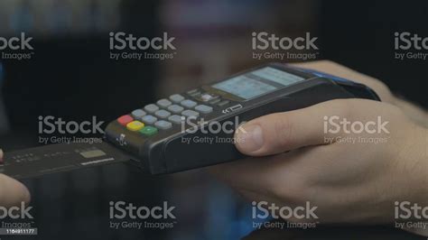 돈 거래를위한 신용 카드 기계 Pos 터미널을 통해 스 와이프 신용 카드와 남자 손과 핀 코드를 입력합니다 전자 화폐의 은행