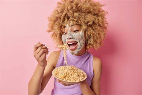 Free Photo Vertical Shot Of Curly Haired Woman Enjoys Eating Junk