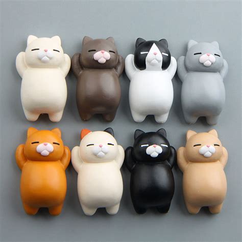 small plastic cat figurines sitting in a row on a gray surface with ...