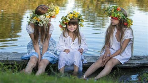 Маленькие девочки в венках на берегу деревенской речки в день Ивана ...