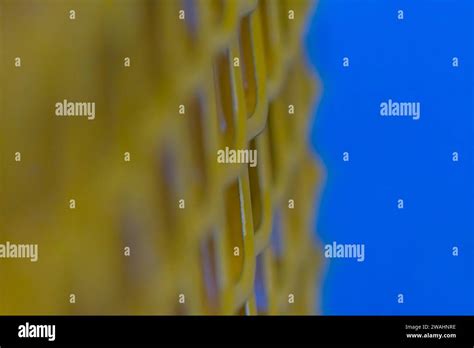 Macro Of Yellow Metal Grate On Blue Background With Blur In Both