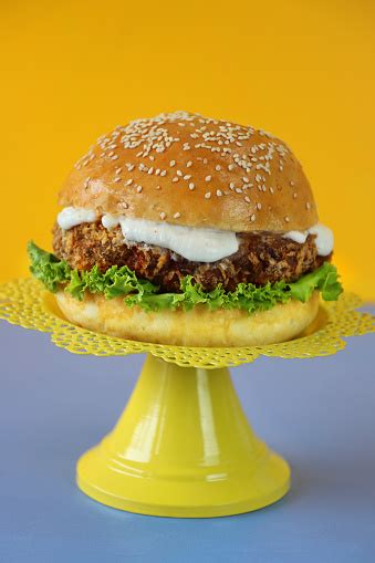 수제 치킨 버거 참깨빵 빵 녹은 치즈와 양상추 분할 보라색 회색과 노란색 배경이 들어있는 노란 케이크 스탠드의 이미지 전경에
