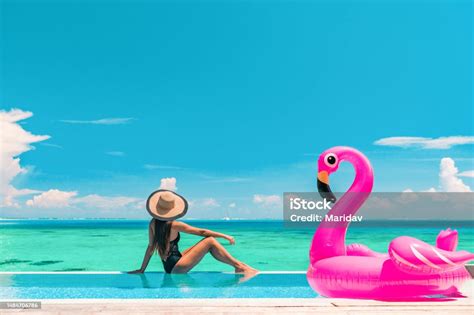 여름 휴가의 재미있는 여자는 풍선 핑크 플라밍고 수영장에서 일광욕을 하고 인피니티 수영장 옆에 떠 있다 수상 빌라 리조트에서의