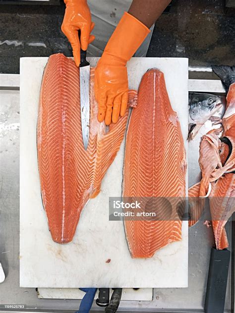 상단 오버 헤드 보기에서 생선 시장 사진에서 전체 연어를 절단 오렌지 장갑을 입고 요리사 뼈 없는 부드러운 살에 대한 스톡 사진