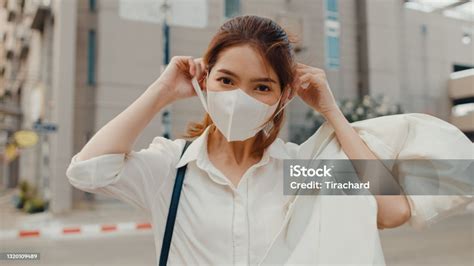 패션 오피스 의류의 성공적인 젊은 아시아 사업가는 도시 현대 도시에서 야외에서 혼자 서있는 동안 웃고 카메라를보고 의료 얼굴