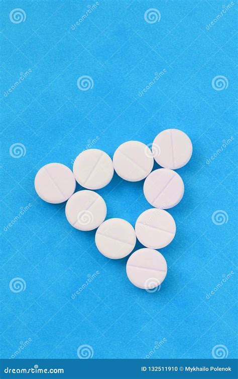 Several White Tablets Lie On A Bright Blue Background In The Form Of An
