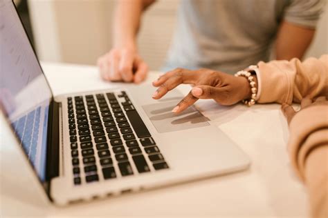 Macbook Pro 근처의 검은 색 및 회색 필름 카메라를 가리키는 사람 · 무료 스톡 사진