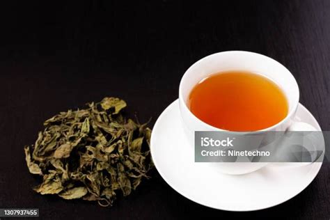 검은 나무 배경에 말린 털시 잎 더미와 흰색 컵에 털시 또는 거룩한 바질 차 찻잔에 대한 스톡 사진 및 기타 이미지 찻잔 0명 갈색 Istock