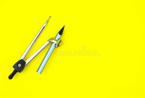 One Compass Attached To A Silver Color Wood Pencil Crayon On A Yellow Background Stock Image