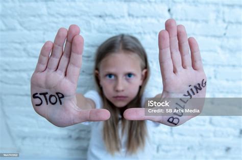 젊은 귀여운 필사적이 고 무서 워 작은 여 학생 그녀의 손에 서 면 왕 따 텍스트 중지 보여주는 어린이 학대와 학교 개념에서 왕 따 극적인 빛 감정에 대한 스톡 사진 및