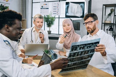 환자의 엑스레이 스캔을 검사하는 테이블에 현대적인 장치를 가진 유능한 다인종 의사 진단을 위해 협력하는 다양한 치료사 그룹 건강 치료 및 의학 개념 사진