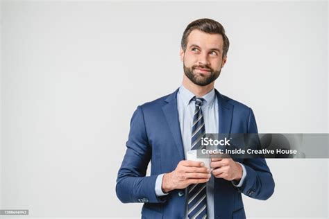 사려 깊은 펜스 코카서스 젊은 잘 생긴 성공적인 사업가 에 정장 입고 들고 뜨거운 음료 차 커피 의 컵 흰색 배경에 고립 된