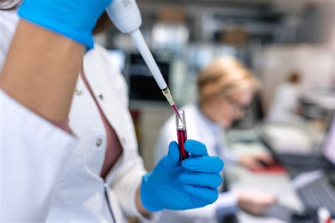 테스트 튜브로 작업 하는 동안 마이크로 파이 펫을 사용 하 여 장갑에서 손의 클로즈업 유전학 연구를 위한 현대 의료 장비를 가진 혁신적인 제약 실험실에 있는 사람들 2명에