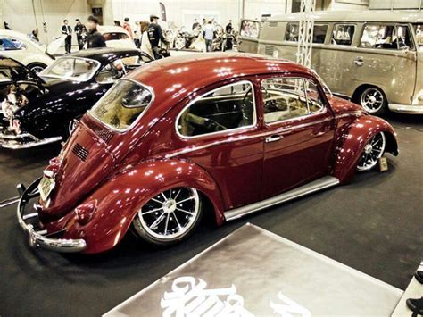 An Antique Car On Display In A Showroom With Other Classic Cars And People Looking At It