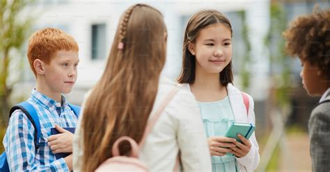 배낭을 메고 야외에서 함께 서서 학교 순간에 대해 토론하는 초등학생 그룹 사진 Unsplash의 행복 이미지