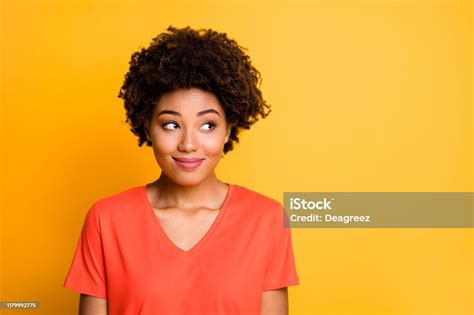 교활한 미소와 함께 측면 빈 공간을 찾고 놀라운 어두운 피부 아가씨의 사진 오렌지 V 목 T 셔츠 고립 된 노란색 색상 배경 T 셔츠에 대한 스톡 사진 및 기타 이미지
