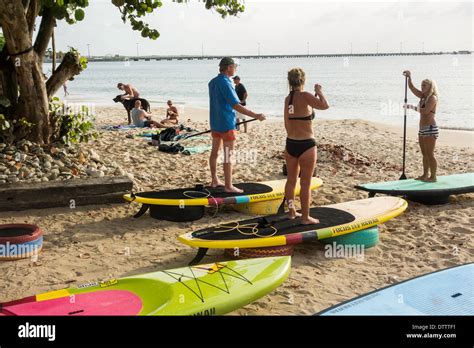 A Blonde Female Instructor Teaches A Class In Stand Up Paddle Boarding To A Caucasian Man And