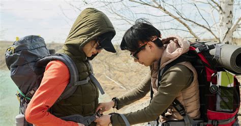 가장 친한 친구 또는 자매와 함께 하이킹하는 젊은 아시아 여성의 측면 모습은 그녀가 무거운 여행 배낭을 조정하고 고치는 것을