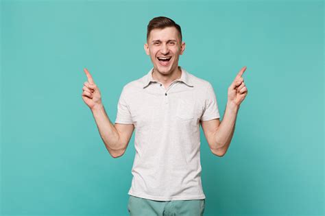 캐주얼에서 쾌활 한 젊은 남자의 초상화를 가리키는 인덱스 손가락 옆에 파란색 청록색 벽 배경에 고립 스튜디오 사람들은 진심으로