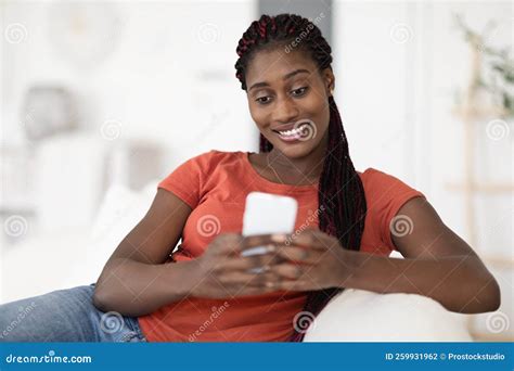 Beautiful Young Black Woman Messaging On Smartphone While Relaxing At