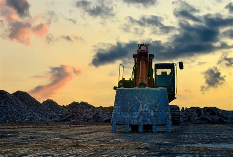 철거에서 콘크리트 및 건설 폐기물을 재활용합니다 디스포사 매립지의 굴삭기 건물 잔해의 재사용 백호는 일몰 배경에 광산 채석장에서 자갈을 파고 0명에 대한 스톡 사진 및 기타
