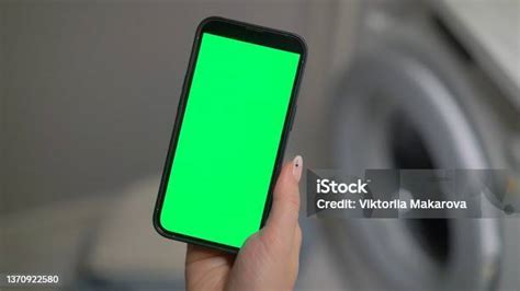 여자는 세탁에 그녀의 손에 녹색 크로마키 화면과 휴대 전화를 보유 Brand Name Smart Phone에 대한 스톡 사진 및